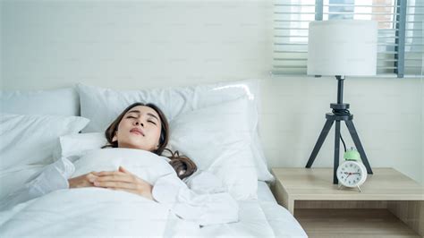 잠옷을 입은 아시아의 아름다운 위안 소녀는 침실에서 잠에서 일어난다 침대에 누워 있는 매력적인 젊은 여성은 아늑한 베개와 담요로 행복을 느끼고 집에서 방에서 일어난 후