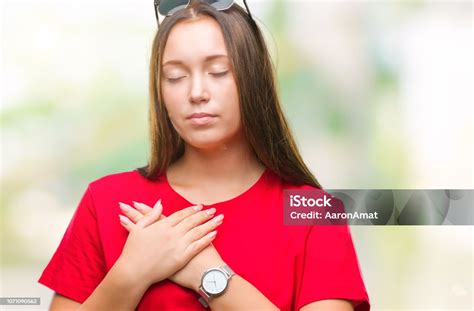 젊은 아름 다운 백인 여자와 웃 고 고립 된 배경 위에 선글라스를 쓰고 얼굴에 닫힌된 눈와 감사와 함께 가슴에 손 건강 개념입니다 갈색 머리에 대한 스톡 사진 및 기타