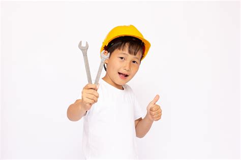딱딱한 모자를 쓴 귀여운 소년이 렌치와 망치를 가진 아이의 손에 오른쪽을 바라본다 개인 보호 장비 및 특수 공구 사용의 중요성의 개념 8 9 살에 대한 스톡 사진 및 기타