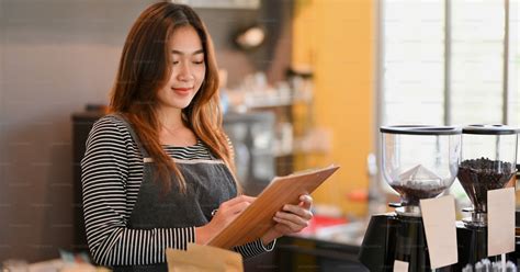 음료 메뉴를 보고 메뉴를 들고 고객으로부터 주문을 받고 커피숍 카페를 보고 있는 예쁜 젊은 바리스타 사진 Unsplash의 태국 이미지