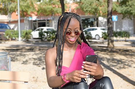 긴 검은 색과 금발 머리띠 앉아 행복 한 아프리카 스타일의 검은 소녀 미소 동안 그녀의 전화와 함께 사진을 찍는다 그녀는 작은