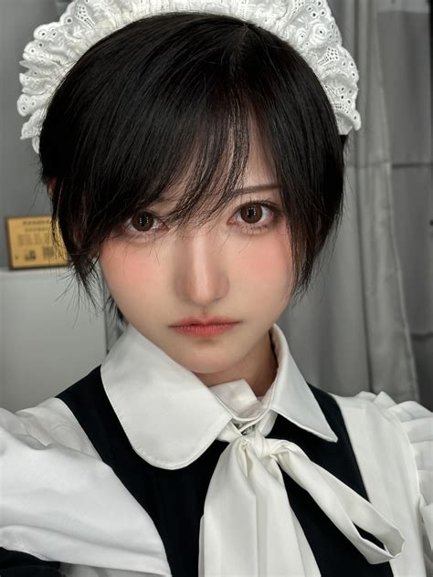 Девушка в костюме горничной позирует для камеры Девушка в костюме горничной сидит элегантно на