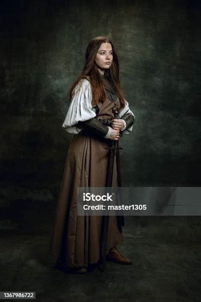 어두운 빈티지 배경에 고립 된 큰 칼과 더러운 상처 얼굴과 중세 전사 또는 기사의 이미지세리우오스 아름다운 여자의 전체 길이 초상화 기사 사람의 역할에 대한 스톡 사진 및