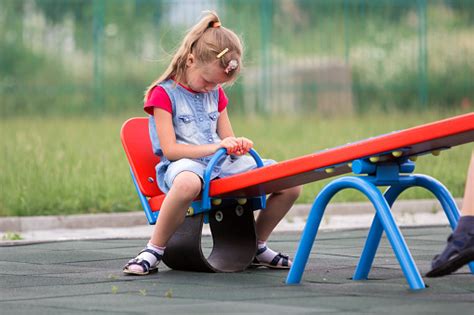 놀이터 충돌 작은 귀여운 젊은 금발의 아이 소녀는 밝은 녹색 흐린 배경에 스윙을 보았다 보고 에 기분 화가 앉아있다 어린 시절의