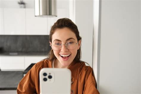 행복한 소녀의 클로즈업 초상화는 스마트폰으로 셀카를 찍고 ⁇ 드폰으로 포즈를 취하고 흥분하고 있습니다 무료 사진