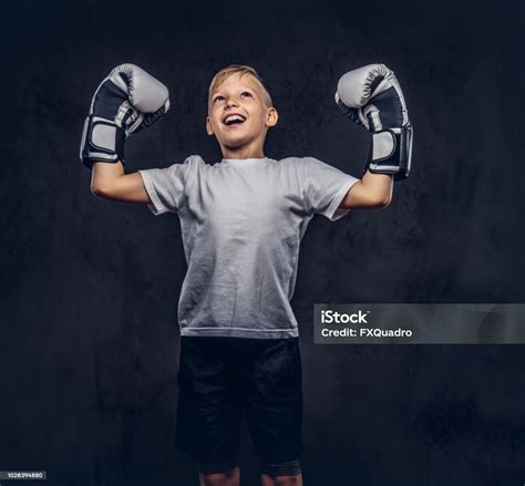 쾌활 한 잘생긴 어린 소년 복 서 흰색 티셔츠 입고 권투 장갑을 입은 금발 머리를 가진 승리에 기 뻐 합니다 에 절연된 어둠 질감된 배경입니다 T 셔츠에 대한 스톡 사진 및