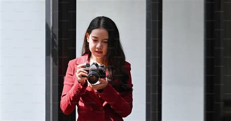 예쁜 젊은 아시아 여성 사진 작가는 창문 근처에 서서 카메라로 사진을 확인합니다 사진 Unsplash의 태국 이미지