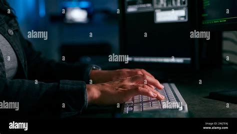 Close Up On Hands Of Female Computer Hacker Sitting In Front Of Screens