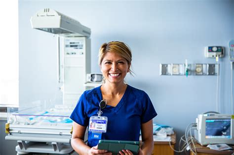 산부인과 병실에서 카메라를 향해 미소 짓고 있는 히스패닉 인종의 수석 간호사의 초상화 간호사에 대한 스톡 사진 및 기타 이미지 간호사 40 49세 Health