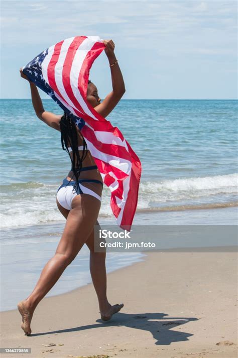 해변을 따라 달리는 동안 미국 국기를 들고 있는 한 젊은 여성의 모습 건강한 생활방식에 대한 스톡 사진 및 기타 이미지 건강한 생활방식 관광객 국가 관광명소 Istock