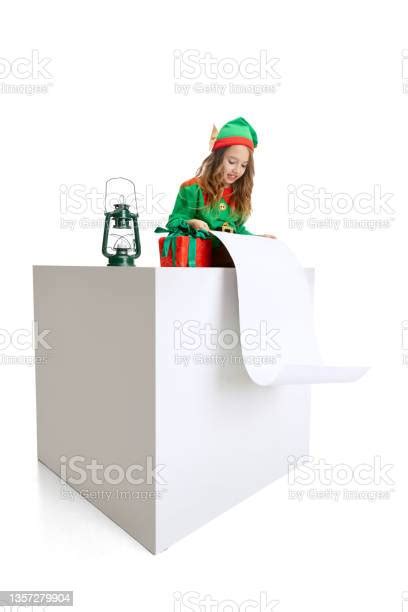 흰색 스튜디오 배경에 고립 된 큰 상자에 앉아 재미있는 노메 또는 엘프처럼 옷을 입은 작은 아름다운 소녀 겨울 휴일 크리스마스 컨셉 6 7 살에 대한 스톡 사진 및 기타