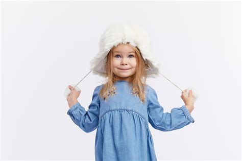 파란색 드레스와 흰색 고립 된 배경에 재미를 가진 겨울 흰색 모피 모자에 작은 놀란 소녀를 미소 12월에 대한 스톡 사진 및 기타 이미지 Istock