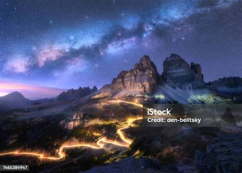 은하수 산길의 자동차 등길 여름의 별이 빛나는 밤의 높은 바위 트레 시메 돌로미티 이탈리아 흐릿한 빛의 흔적 언덕 산봉우리 별이
