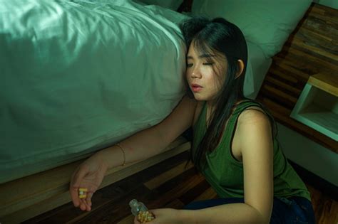 젊은 아름다운 절망과 낭비 중독자 아시아 한국 여성은 아픈 느낌과 우울한 고통 우울증 고장 에 가정 침실 바닥에서 약물 과다 복용 건강관리와 의술에 대한 스톡 사진 및 기타