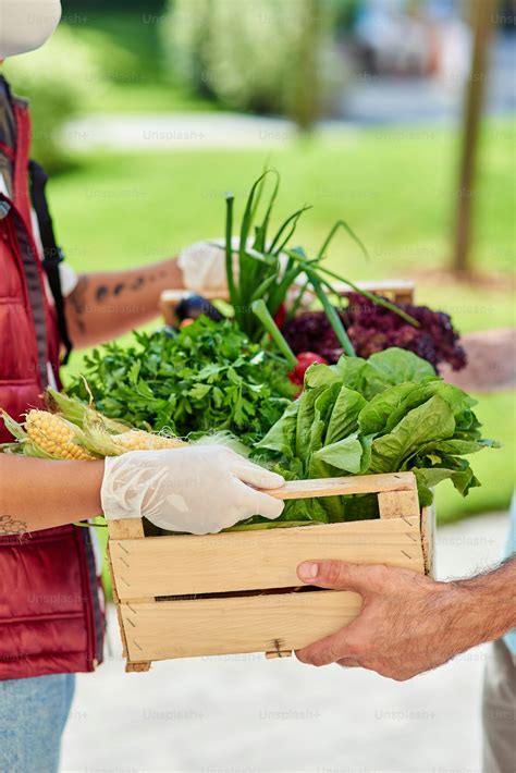집에 계세요 햇볕이 잘 드는 거리에 서 있는 동안 고객에게 신선한 식료품이 담긴 나무 상자를 배달하는 보호 마스크와 장갑을 낀