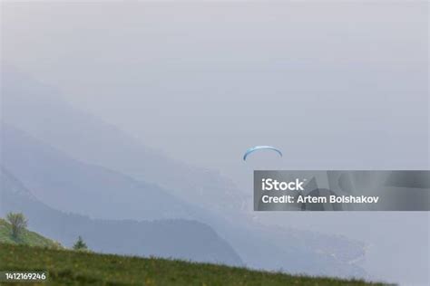 고독한 패러 글라이더가 여름 안개에 높이 솟아 오르고 가르다 호수의 숲이 우거진 산악 동쪽 해안 위로 솟아 오릅니다 말세신 베로나 이탈리아 0명에 대한 스톡 사진 및 기타