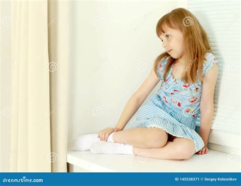 Ein Kleines M Dchen Sitzt Am Fenster Mit Jalousie Stockbild Bild Von