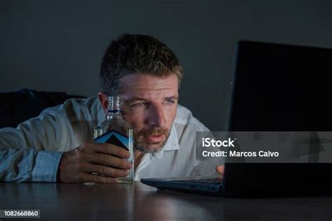 젊은 낭비 및 우울 알코올 중독자 사업가 마시는 병 고통 우울증과 알코올 중독 문제 음주 사무실 노트북 컴퓨터 책상에서 일 하는 술에 취해 늦은 밤 Health에 대한 스톡