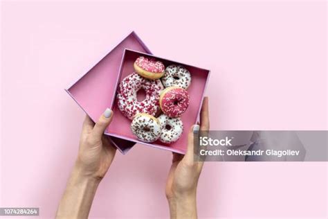 여자 손 분홍색 배경에 도너츠와 오픈 상자를 들고 평면 위치 스타일입니다 공간에 복사 합니다 건강에 좋지 않은 음식에 대한 스톡 사진 및 기타 이미지 Istock