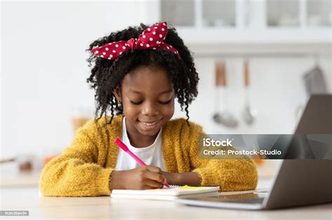 부엌에서 노트북으로 공부하는 동안 메모장에 쓰는 흑인 여성 아이 쓰기에 대한 스톡 사진 및 기타 이미지 쓰기 격리 아이 Istock