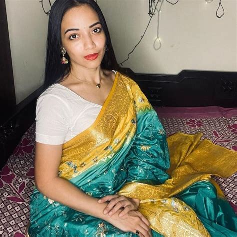 A Woman Sitting On The Floor Wearing A Green And Gold Sari