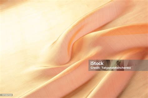 배경 질감 패턴입니다 피복은 주황색 노란 실크 직물 배경은 우아하고 부드러운 있습니다 밝은 공단 직물을 배경으로 사용 하기 위해 접혀 직물 섬유 표면의 위 유형입니다 텍스트