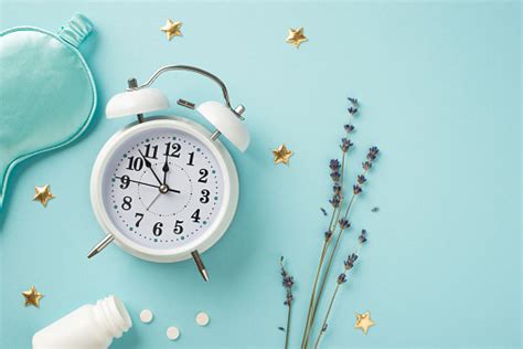 고립 된 파스텔 블루 배경에 알약과 황금 별과 라벤더 블루 실크 수면 마스크 오픈 병의 흰색 알람 시계 Sprig의 상단 보기 사진 개념에 대한 스톡 사진 및 기타 이미지