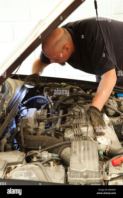 Technician Checking Under The Hood Bonnet Of A Car During An Mot