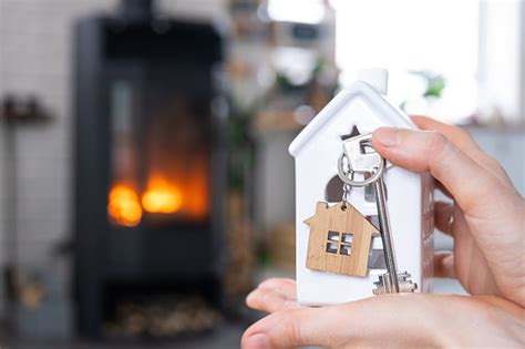 열쇠 고리가 있는 집 열쇠는 벽난로 스토브에 맞서 불길과 장작이 있습니다 아늑한 집 난로 건물 설계 프로젝트 새 집으로 이사 모기지 임대 및 부동산 구매 가정 난방에 대한