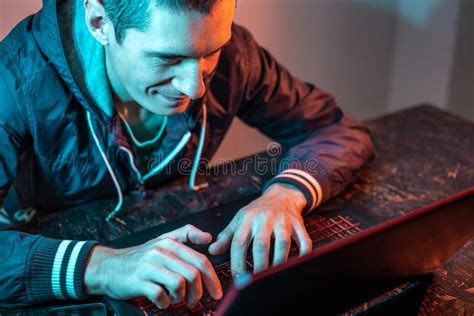 A Male Hacker Is Typing On A Laptop Keyboard In A Dark Room Under A