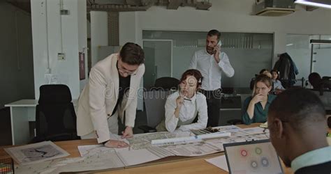 Multicultural Business Team Collaborates On Blueprints In A Modern Office Stock Footage Video