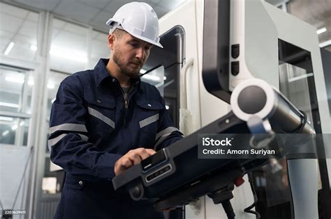 남성 엔지니어가 공장의 모니터에서 Cnc 기계를 제어합니다 공장에서 안전 유니폼과 헬멧을 착용한 선반 기계로 작업하는 남성 공장 노동자 30 34세에 대한 스톡 사진 및