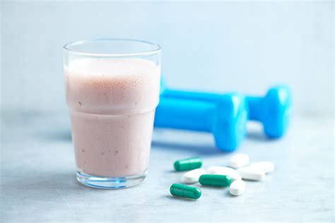 우유와 라즈베리가 포함 된 단백질 셰이크 유리 Bcaa 아미노산 L카 르 니 틴 캡슐 및 블루 덤 벨 배경 스포츠 영양 돌나무 배경입니다 복사 공간 0명에 대한 스톡 사진