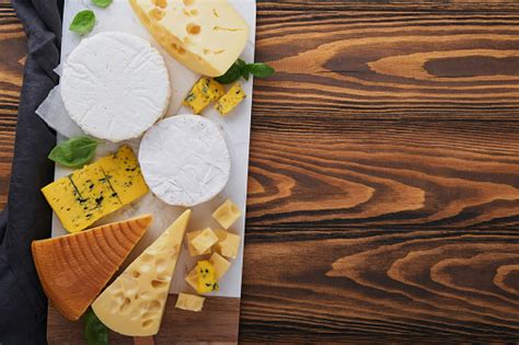 세트 또는 구색 치즈 Maasdam 훈제 치즈 카망베르 블루 치즈 파르 메산 흰색 대리석 보드 갈색 나무 오래된 배경에 바질과 후추와 함께 브리 치즈 상단 보기 사용 가능한