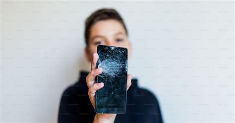 깨진 유리 화면 스마트폰이 화가 난 소년 흰색 배경의 손에 있습니다 집에서 깨진 스마트폰을 들고 걱정하는 아이 사진 Unsplash의 사람 이미지