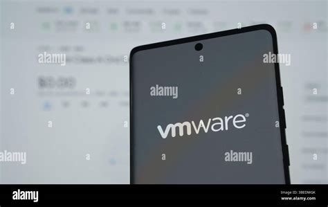 Vmware Logo On A Smartphone Screen Against A Blurred Financial Chart