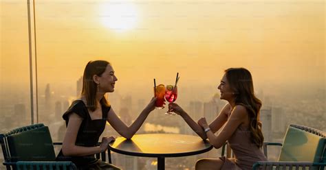 아름다운 아시아 여자 친구들이 여름 해질녘 대도시의 마천루 옥상 레스토랑에서 만나 칵테일을 마신다 여자 친구는 밤에 도시에서 야외 라이프 스타일 활동을 즐긴다 사진