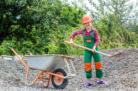 건축업자와 건설의 게임 야외 활동 개념입니다 수레에 잔해를 운반하는 소녀 건설 작업 소녀 건축업자는 잔해 삽을 가져갑니다 열심히 일하는 청소년 십대에 대한 스톡 사진 및