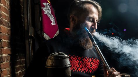 전통적인 후카 파이프를 흡연 하는 남자의 클로즈업 사진 어두운 배경에 Hookah 카페에서 연기를 내뿜는 남자 후카 또는 수도