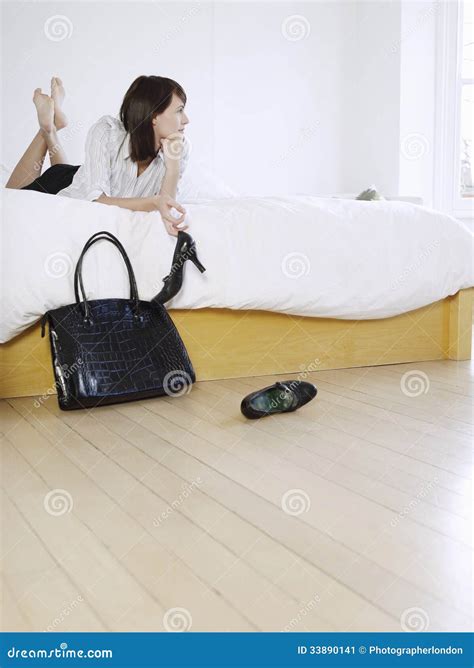 Женщина держа ботинок пока лежащ в кровати Стоковое Изображение изображение насчитывающей