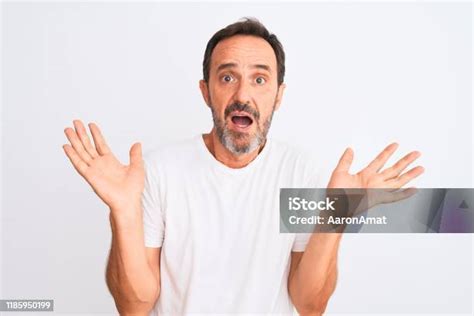 중년의 잘생긴 남자는 고립 된 흰색 배경 에 서 캐주얼 티셔츠를 입고 팔과 손을 들고 혼란 스러운 표정 의심 개념 T 셔츠에 대한 스톡 사진 및 기타 이미지 Istock