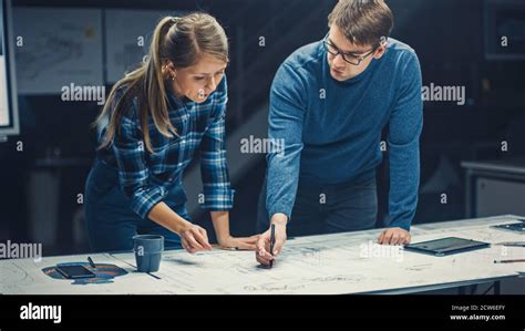 In The Dark Industrial Design Engineering Facility Male And Female Engineers Talk And Work On A