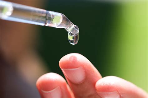 아름다운 여성의 손은 손 부드러운 빛 배경에 얼굴의 혈청 콜라겐 보습제를 삭제 보호피부 트리트먼트 페이셜 에센스 오일 비타민 C 뷰티 및 스파 컨셉 건강관리와 의술에 대한