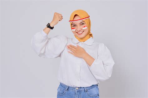 8월 17일 인도네시아 독립기념일을 축하하는 동안 히잡을 쓰고 경례하는 제스처를 보여주는 흥분한 젊은 아시아 무슬림 여성이 흰색 배경 위에 고립되어 있다 독립에 대한 스톡