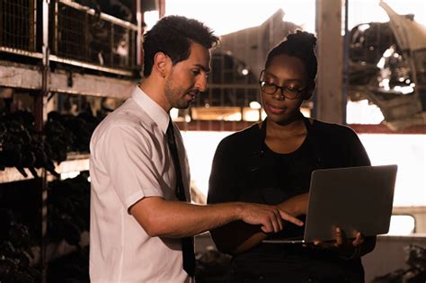 두 사람의 다양성 백인 비즈니스 매니저 는 흑인 아프리카 노동자 여성과 진지하게 이야기하고 공장 창고에서 컴퓨터 노트북에 대한 보고서를 가리키는 경영자에 대한 스톡 사진 및