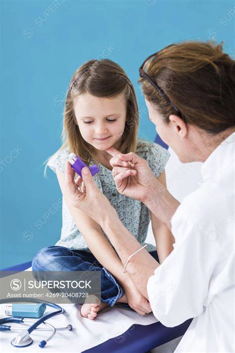Doctor Instructing A Girl On How To Use An Asthma Inhaler SuperStock