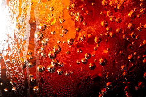 어두운 콜라 배경의 얼음 조각의 보기를 닫습니다 유리 벽에 거품과 매크로 거품과 시원한 달콤한 여름 음료의 질감 표면의 상단까지 떠 있거나 피징 0명에 대한 스톡 사진 및