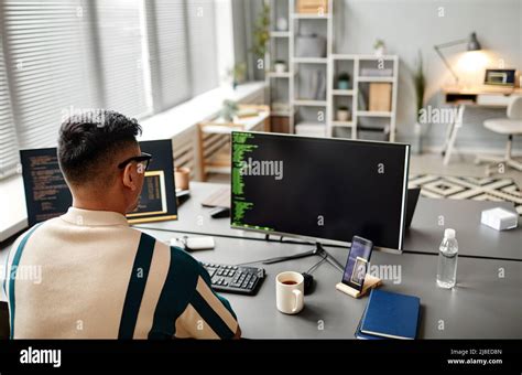 Back View Of Male It Developer Typing On Keyboard With Programming Code On Computer Screen While