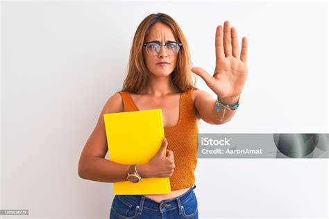 안경을 쓰고 있는 젊은 아름다운 빨간 머리 여자는 진지하고 자신감있는 표정 방어 제스처로 정지 표지판을하는 열린 손으로 고립 된