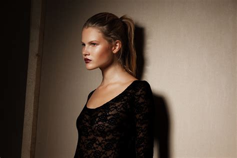 꼬리에 단단한 머리를 가진 검은 색 바디 수트를 입은 여성 모델 스튜디오에서 포즈를 취하고 프로필 어두운 배경을 찾고 있습니다 14 15 살에 대한 스톡 사진 및 기타